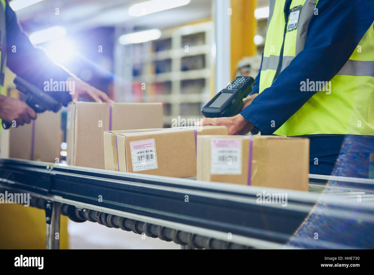 Workers scanning and processing boxes on conveyor belt in distribution ...