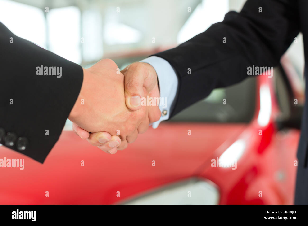 handshake of two men in suits against red car Stock Photo - Alamy