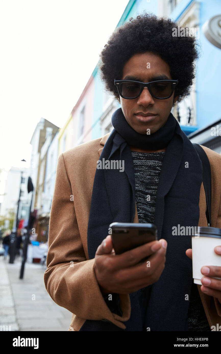 Young Man Using Phone On Busy City Street Stock Photo - Alamy