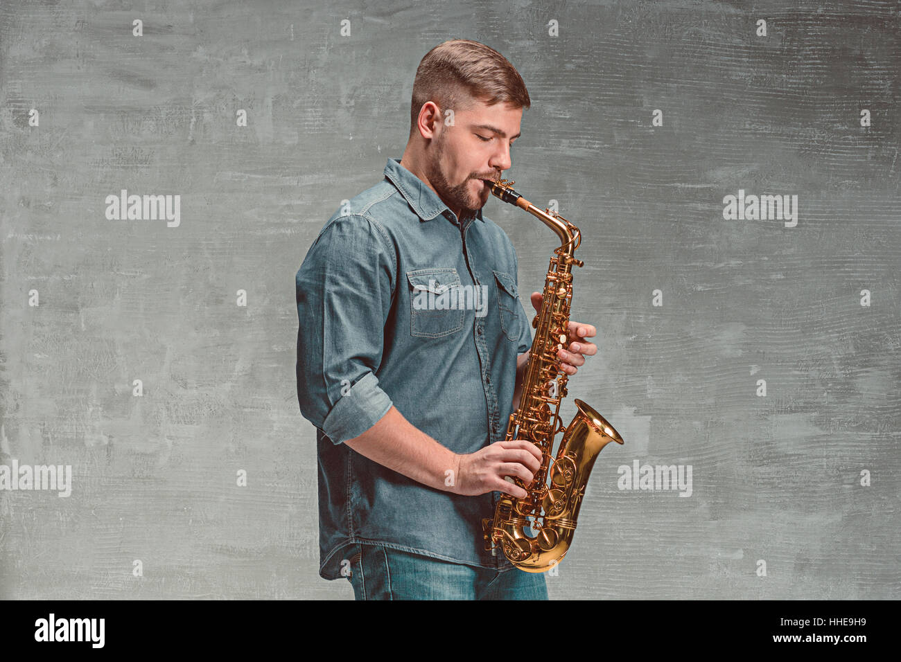 Happy saxophonist playing music on sax over gray background Stock Photo ...
