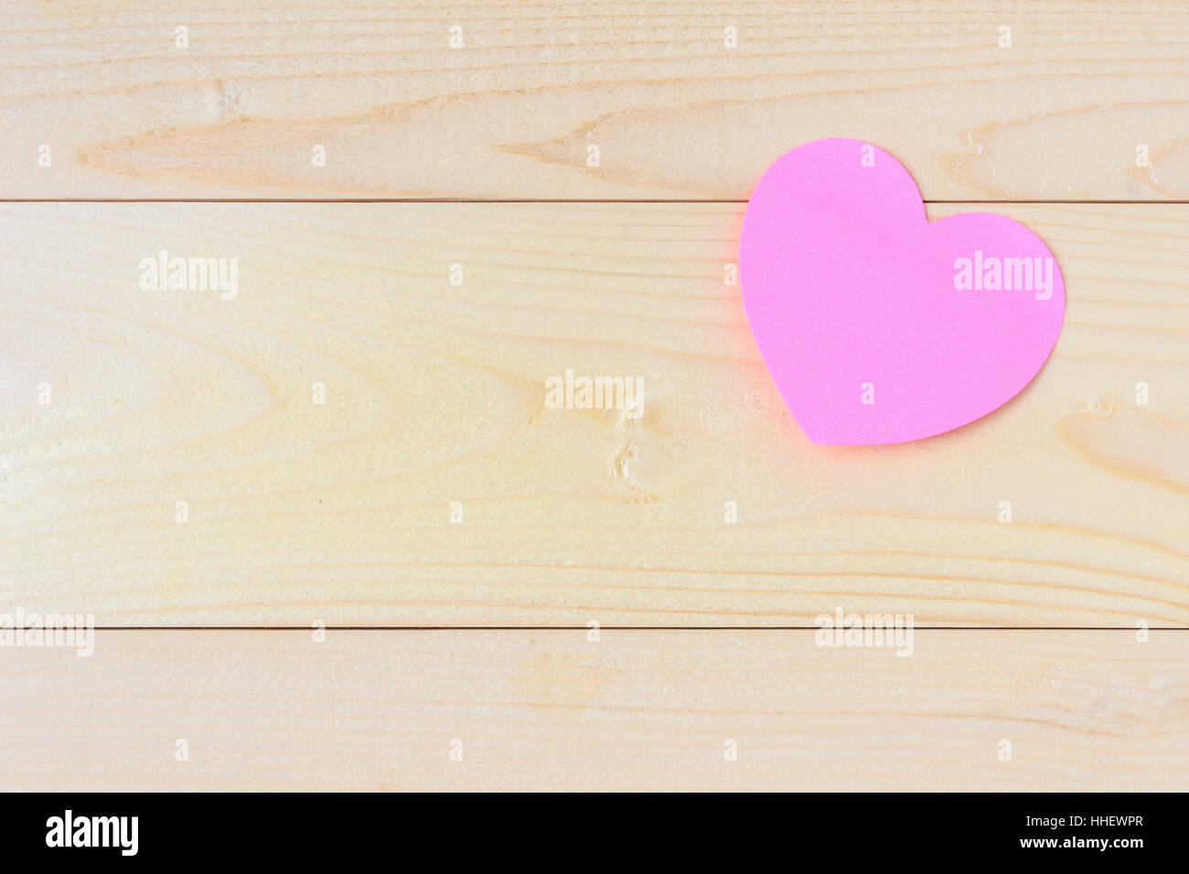Pink sticky notes hearts shaped holes on wooden background with copy ...