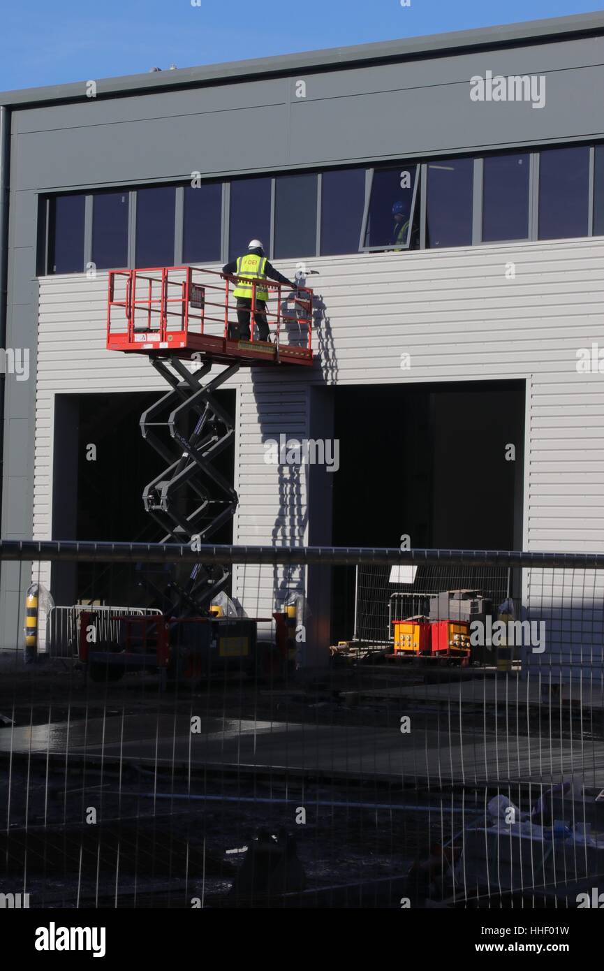 A worker working at height from a scissor platform tower wearing his ...