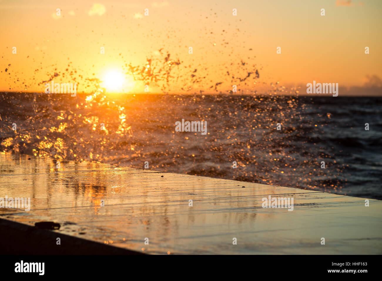 wavebreaker in the sea with waves crushing over in sunset Stock Photo ...