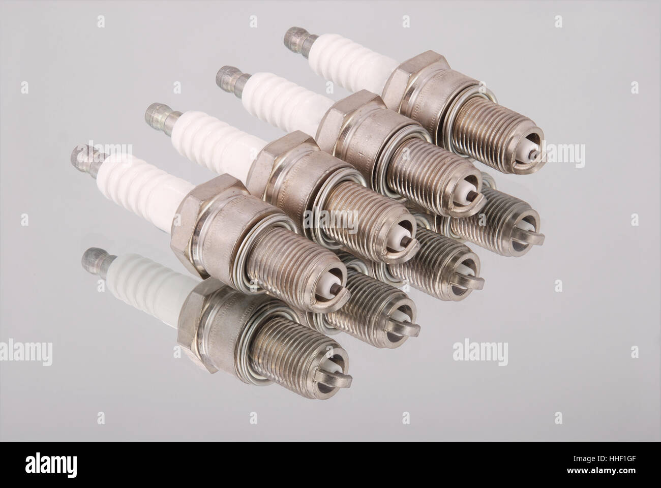 Four new spark plugs on a mirror background Stock Photo - Alamy
