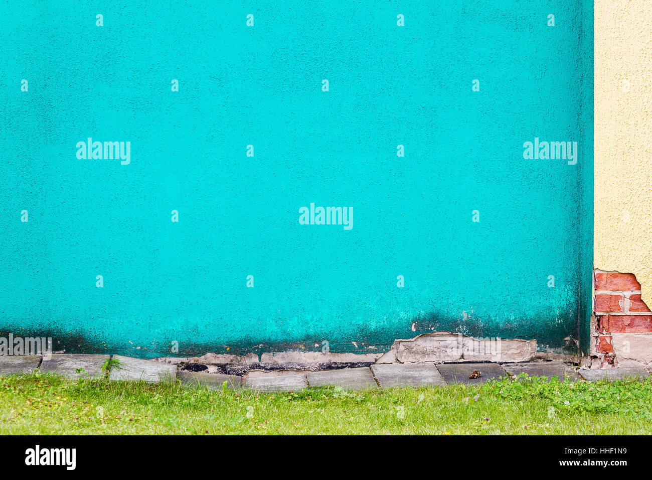 Vibrant cyan plaster wall with green grass Stock Photo - Alamy