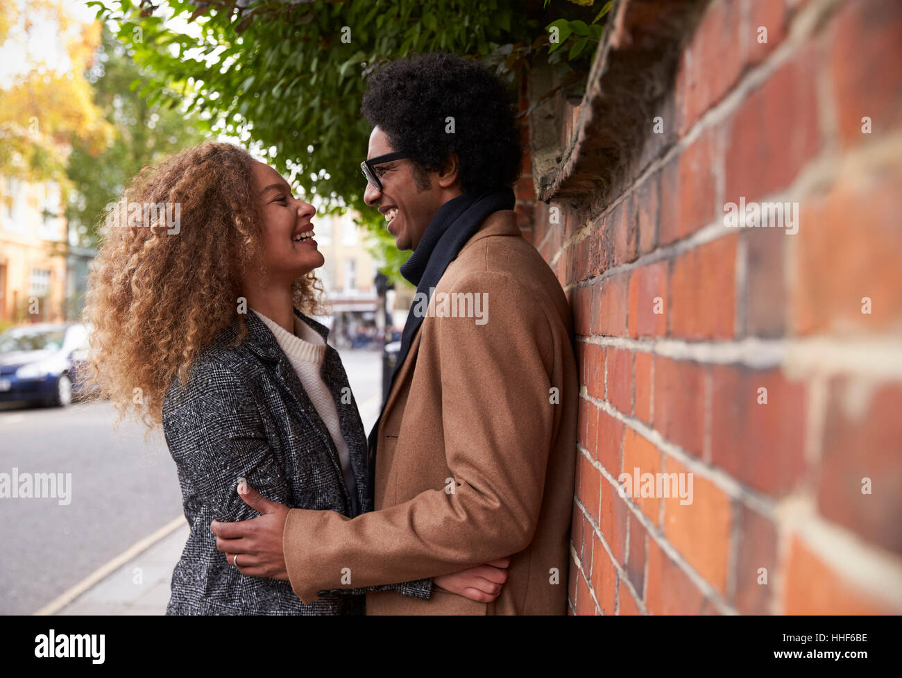 Couple Standing By Wall On City Street And Hugging Stock Photo - Alamy
