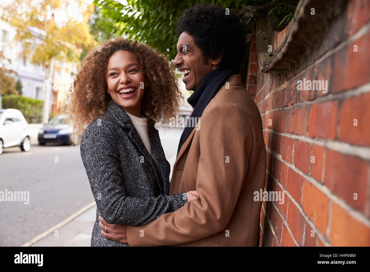 Couple Standing By Wall On City Street And Hugging Stock Photo - Alamy