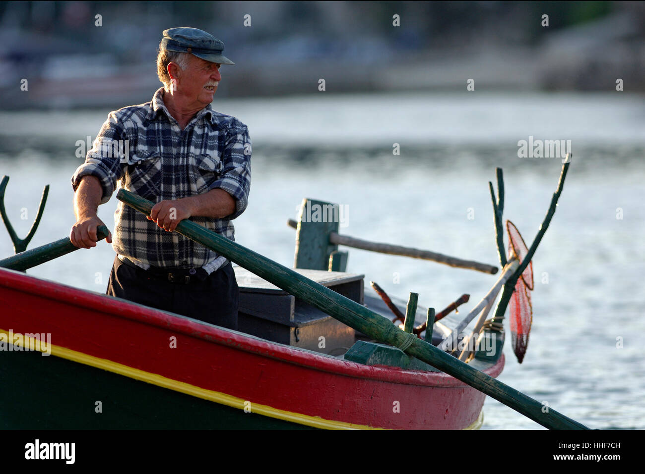 Greek Fisherman rowing out to sea in wooden painted boat Stock Photo ...