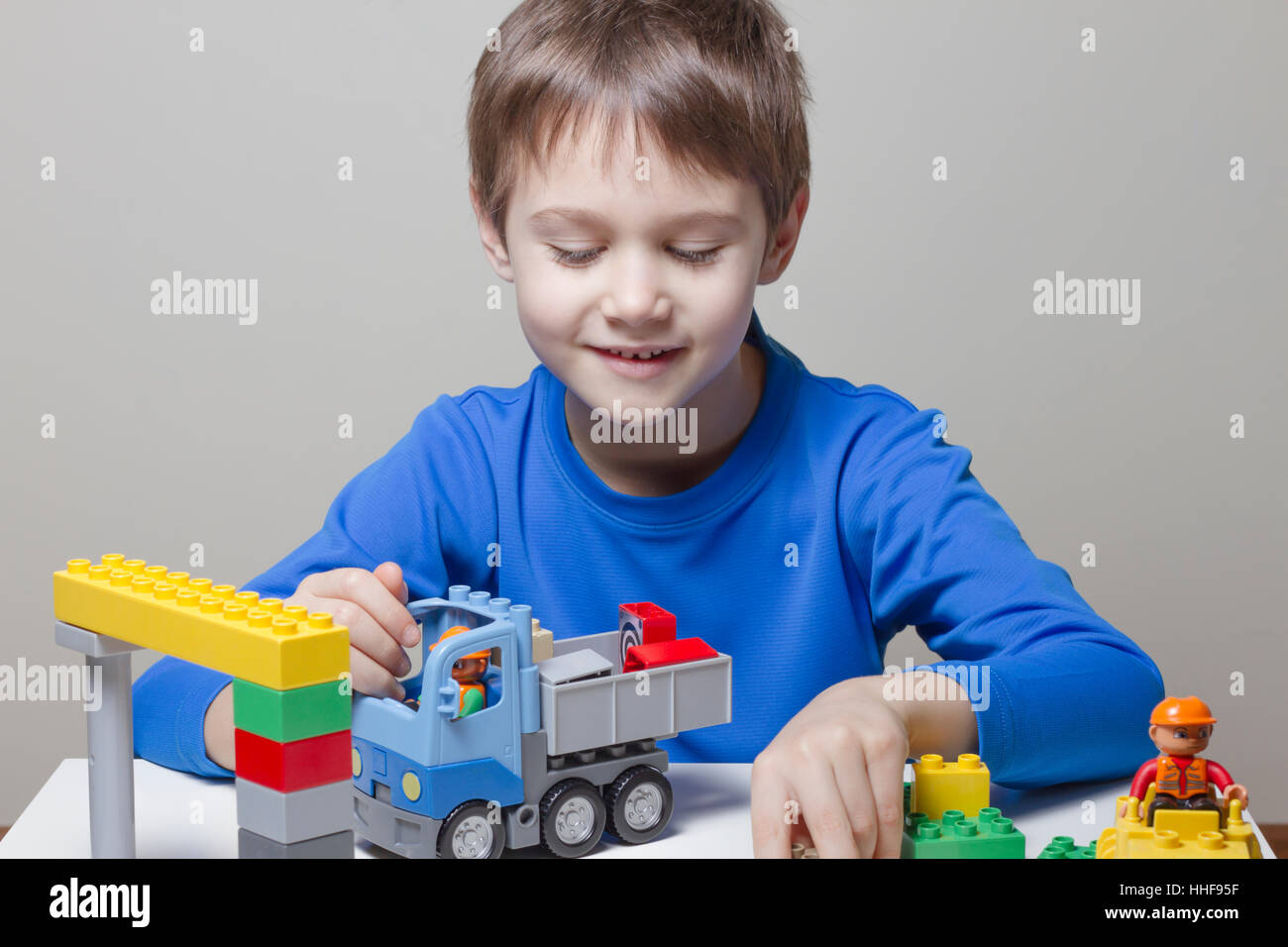 Happy kid boy playing with colorful plastic construction bricks at home ...