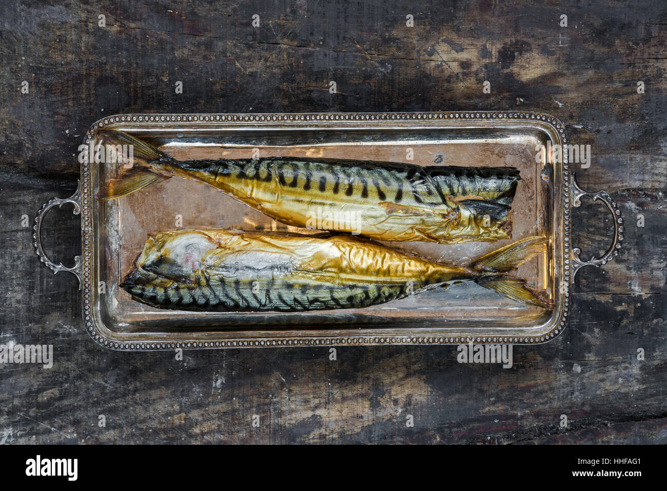 Two smoked mackerel fish on silver tray placed on wooden board - top ...