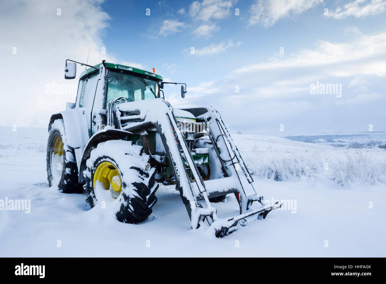 Snow covered green tractor with yellow wheel hubs in North York Moors ...