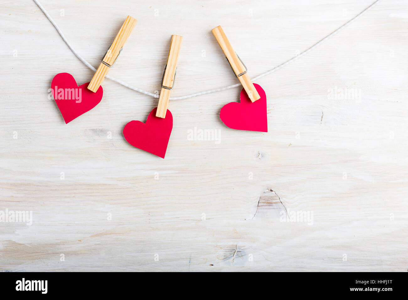Three red paper hearts hanging on string with mini clothes pin over ...