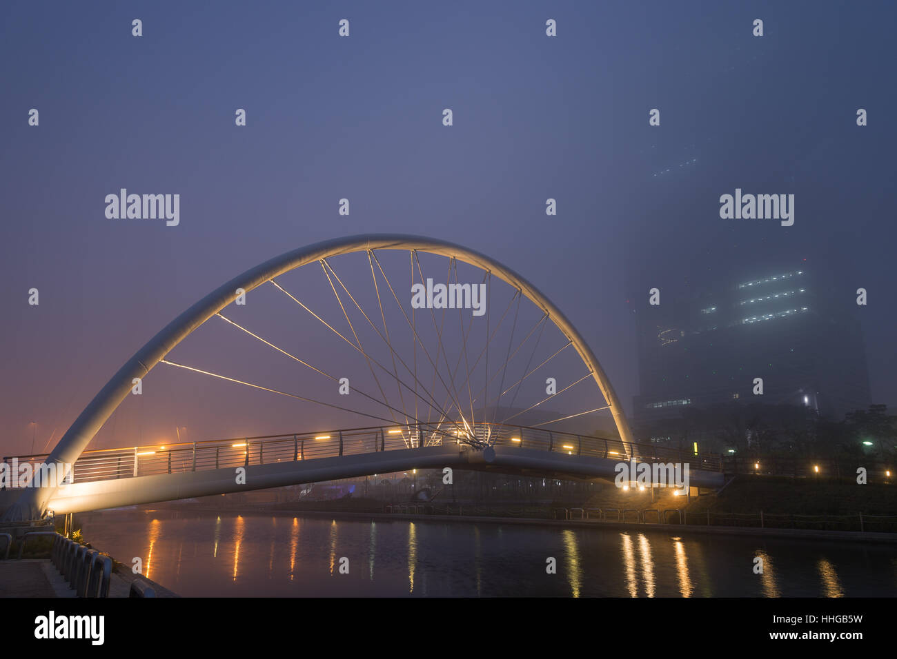 Foggy view of a river, lit bridge and skyscraper in Incheon, South ...