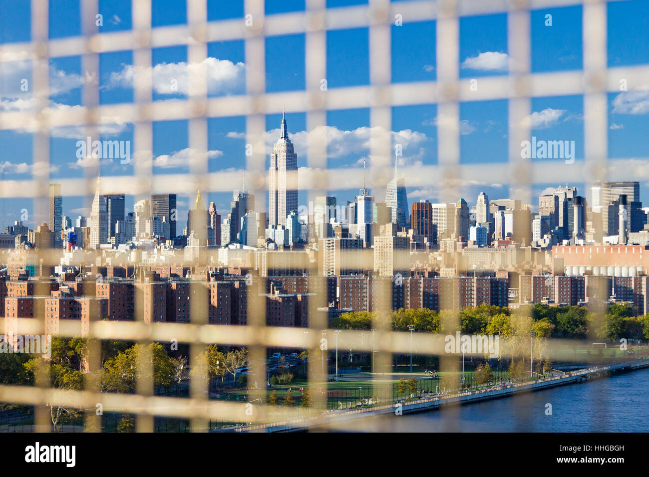 NYC downtown skyline skyscrapers view seen through the bars of a fence ...