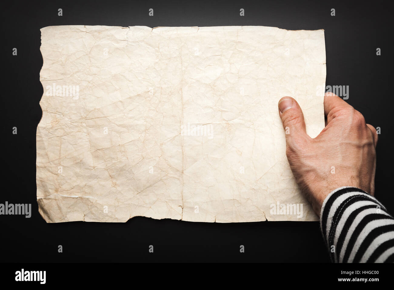 Strong sailor hand holds empty old crumpled paper sheet over black ...
