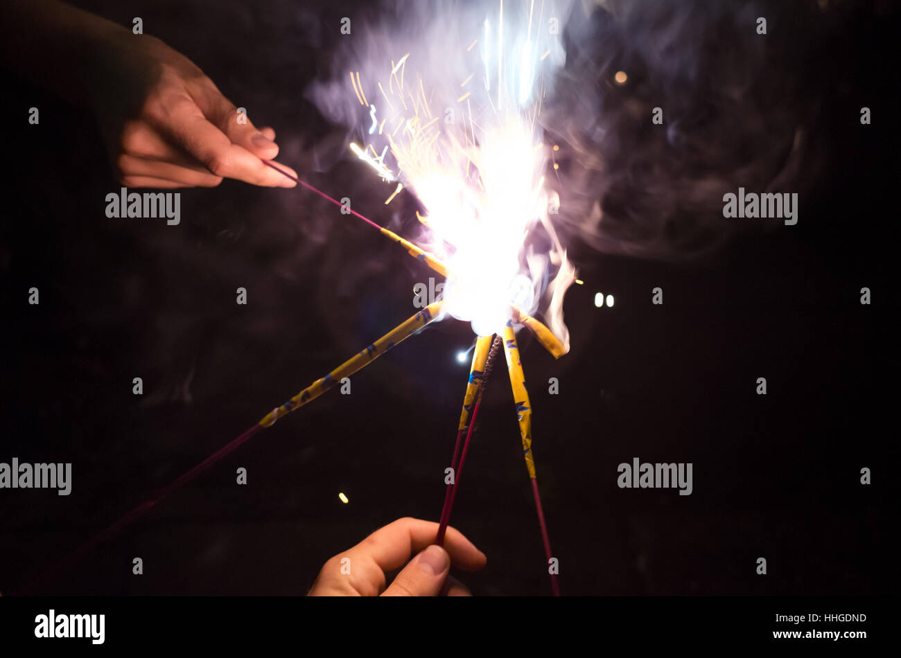 Close-up of hands coming together to ignite sparklers (fireworks ...
