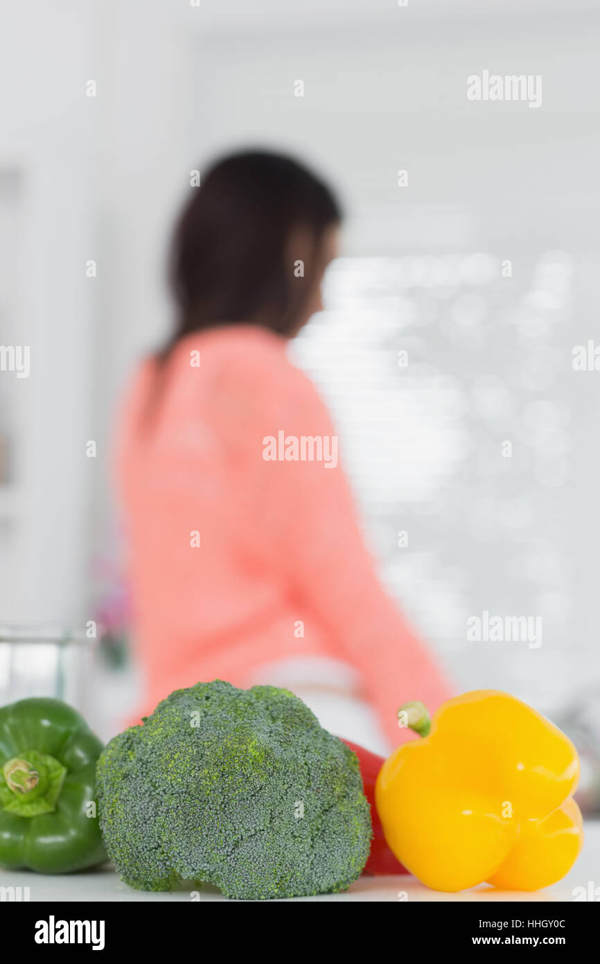 Vegetables with woman cooking in background in a kitchen Stock Photo ...