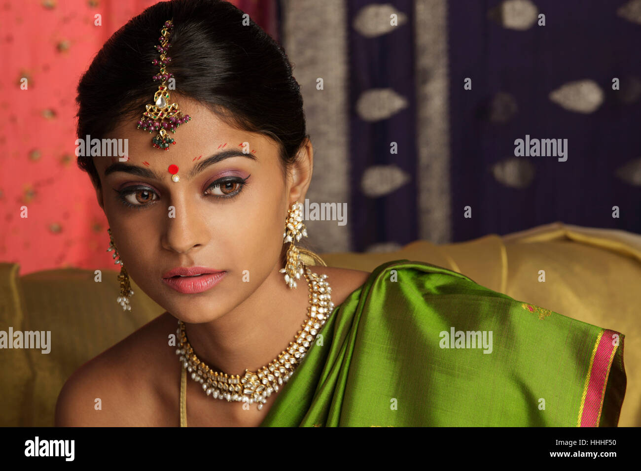 woman wearing sari, surrounded by sari fabric, decorated with henna ...