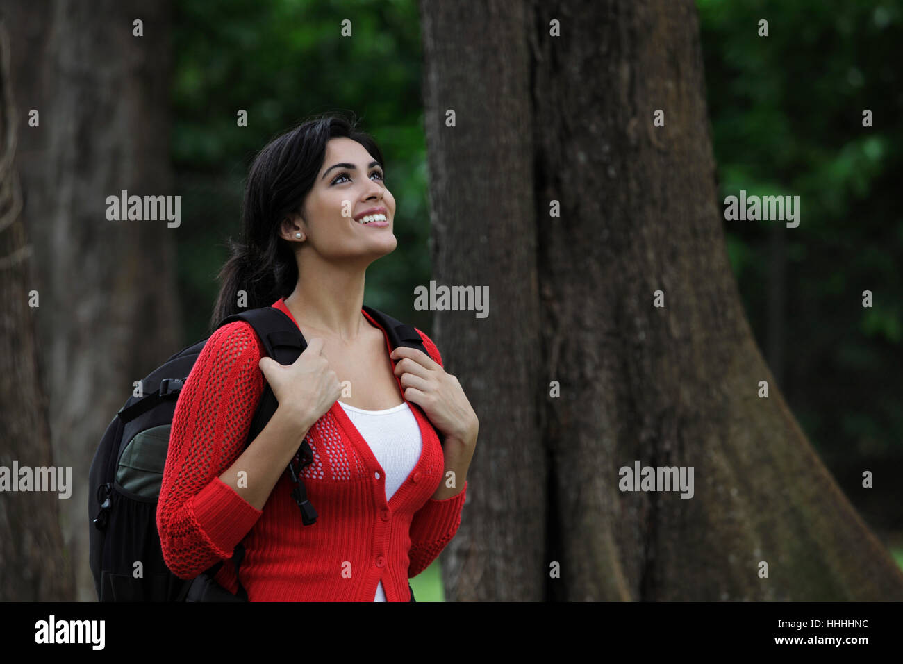 Young woman wearing a back pack looking up at trees and smiling Stock ...