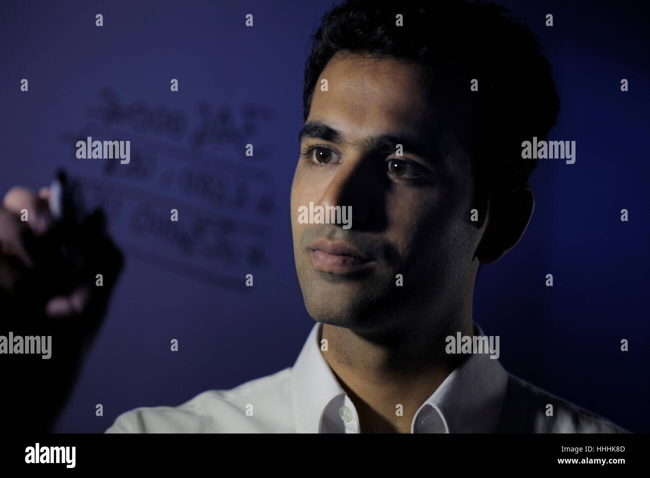 Young man writing on transparent glass wall Stock Photo - Alamy