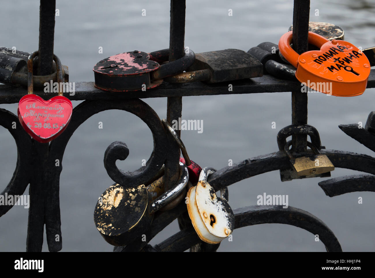 Multiple padlocks of various sizes, shapes and colors locked to a black ...