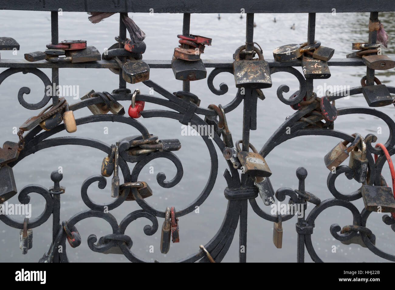 Multiple padlocks of various sizes, shapes and colors locked to a black ...
