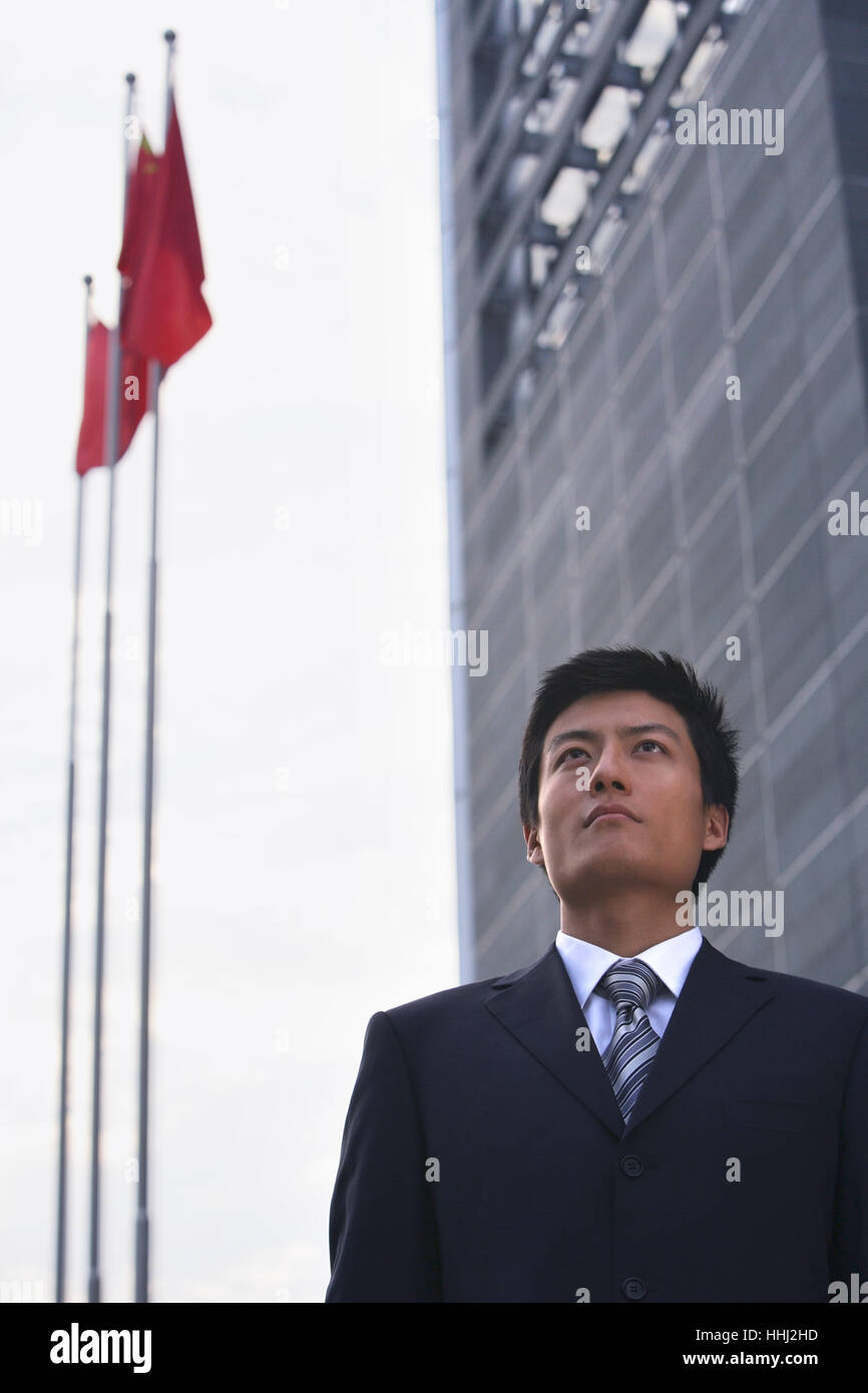 A businessman stands in front of a building with flags Stock Photo - Alamy