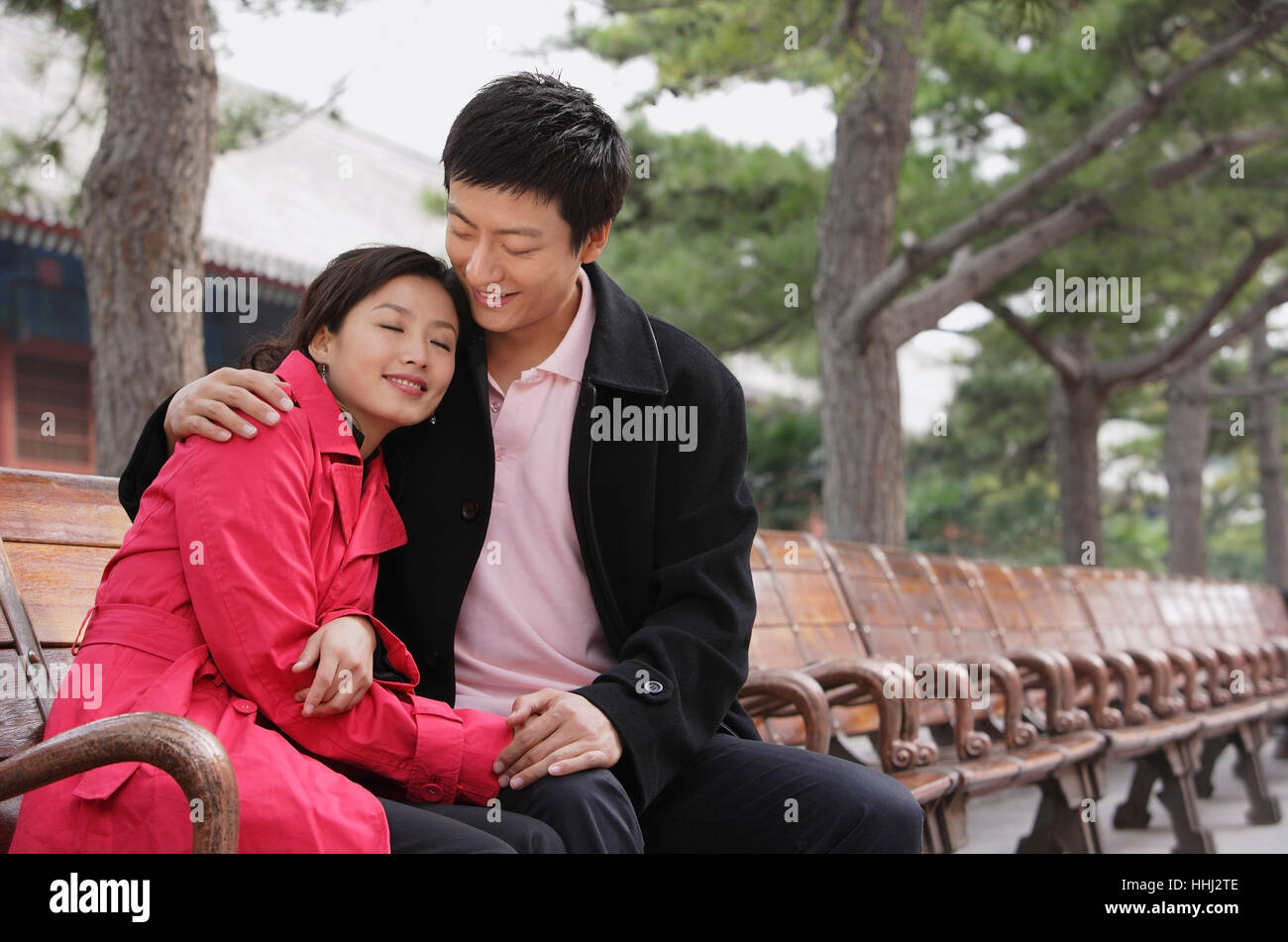 A couple cuddle as they sit down Stock Photo - Alamy