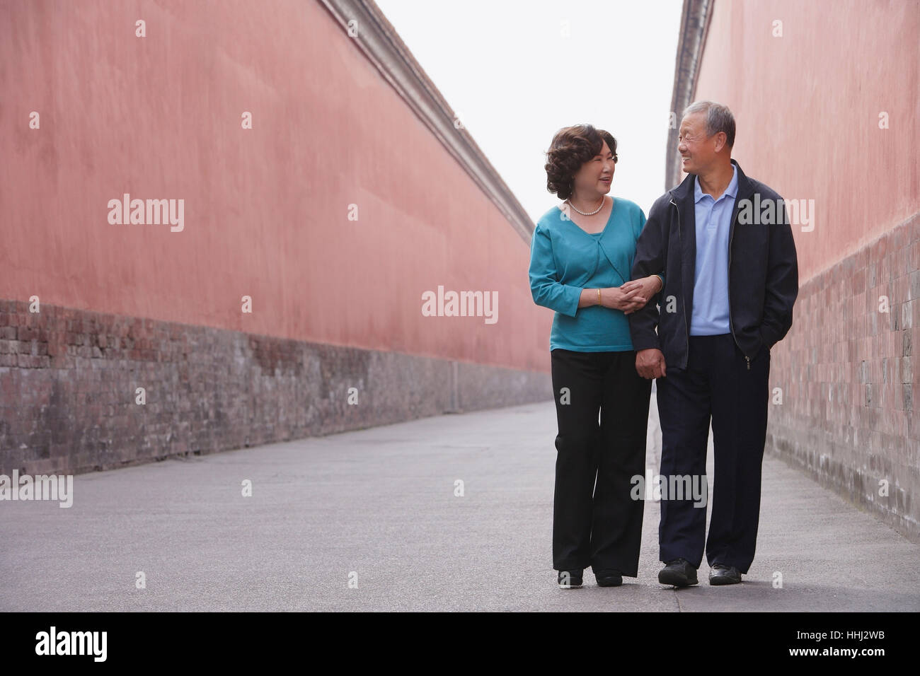 A man and woman link arms as they walk together Stock Photo - Alamy