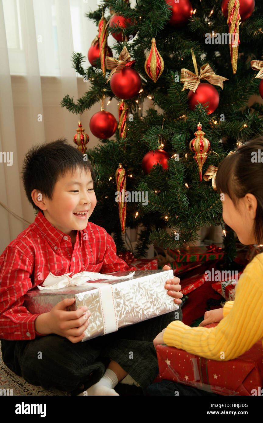 Children with presents sitting under Christmas tree Stock Photo - Alamy