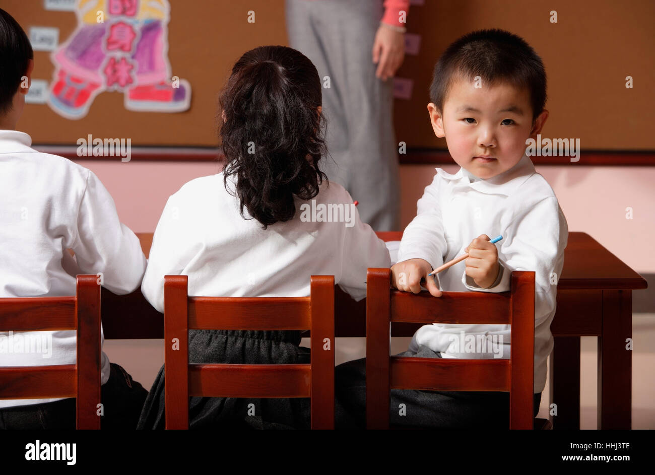 Students in class with teacher, schoolboy turning head around looking ...