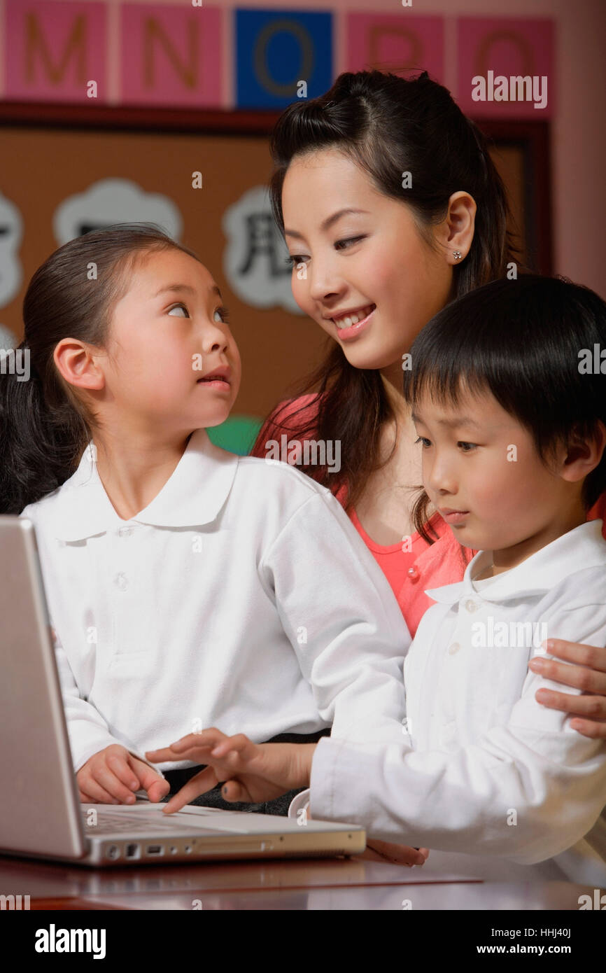 Young school children with their teacher using laptop Stock Photo - Alamy