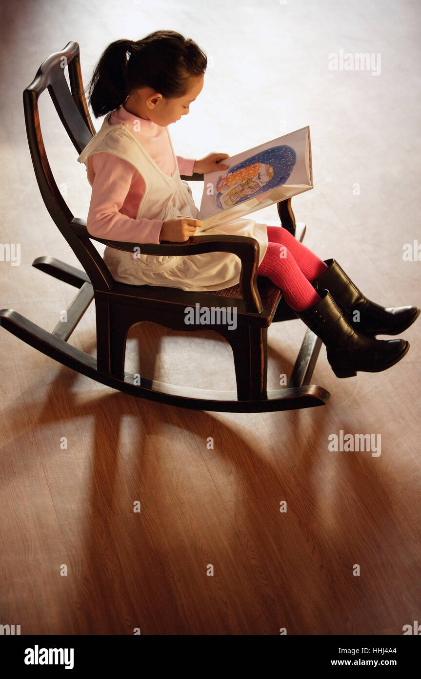 Girl sitting in rocking chair, reading a book Stock Photo - Alamy