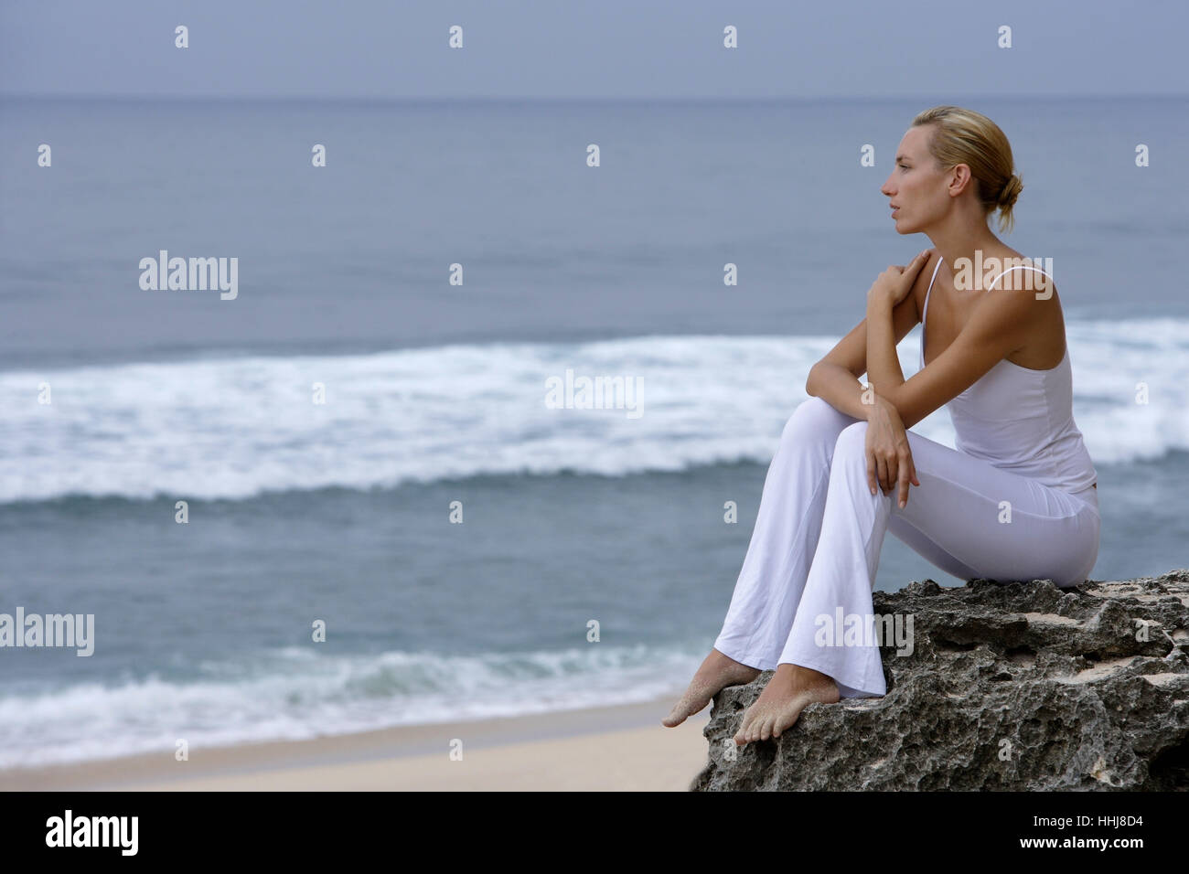 woman sitting on rocks watching ocean Stock Photo - Alamy