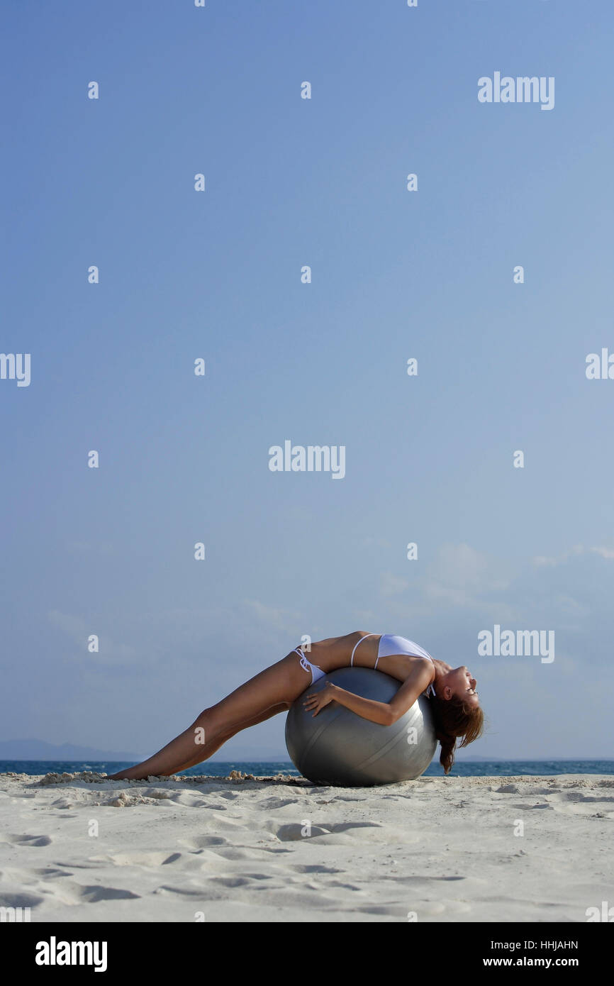 woman in bikini lying on giant ball on beach Stock Photo - Alamy
