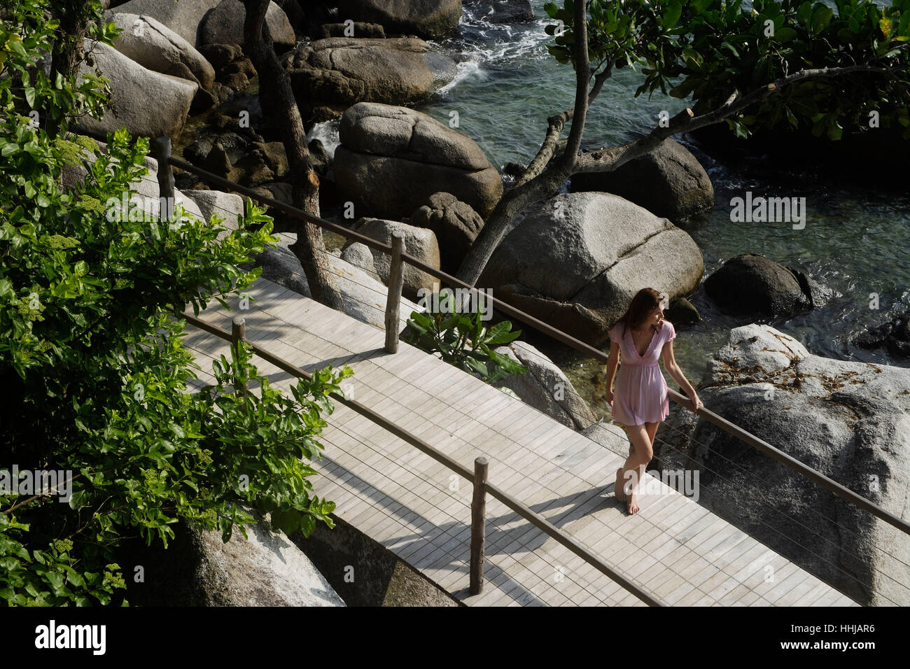 young woman standing on bridge looking at ocean Stock Photo - Alamy