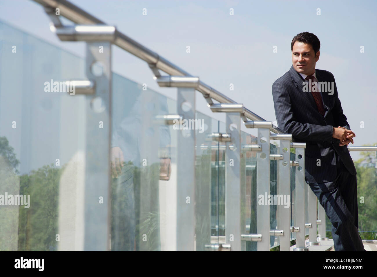 businessman leaning against railing on balcony Stock Photo - Alamy