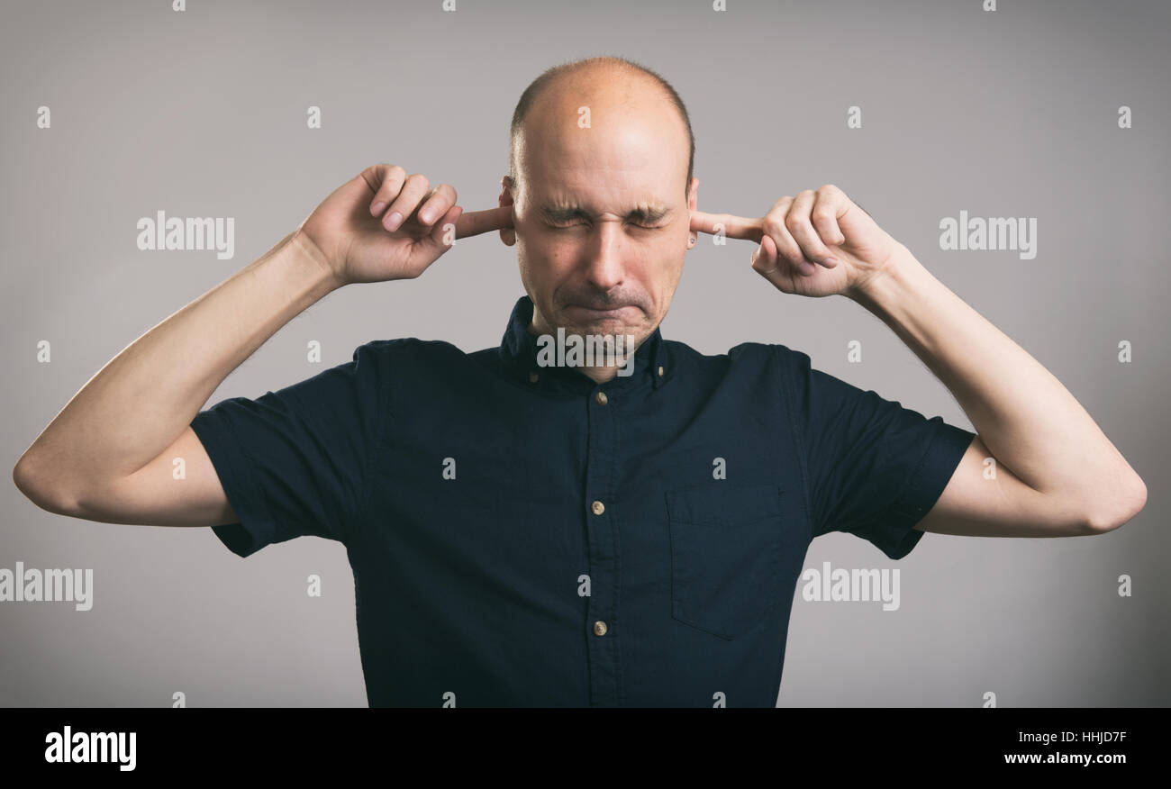 bald man covering his ears over gray background Stock Photo - Alamy