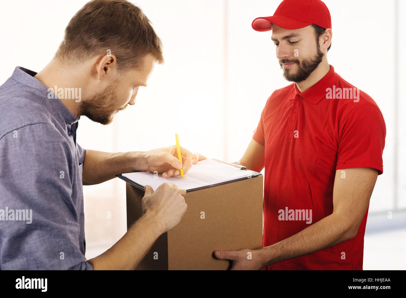 delivery service - man signing delivery receipt of box Stock Photo - Alamy