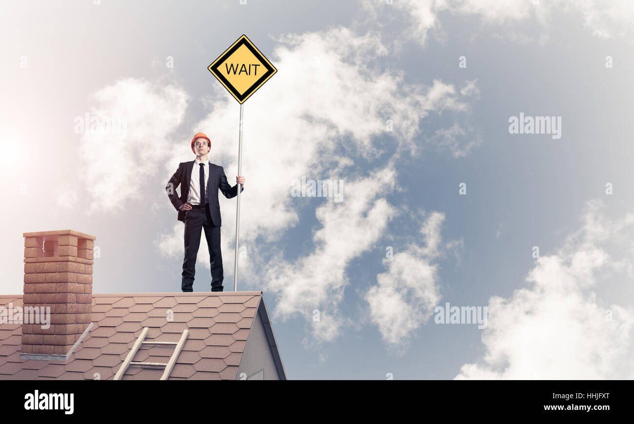 Young businessman on house brick roof holding yellow signboard Stock ...