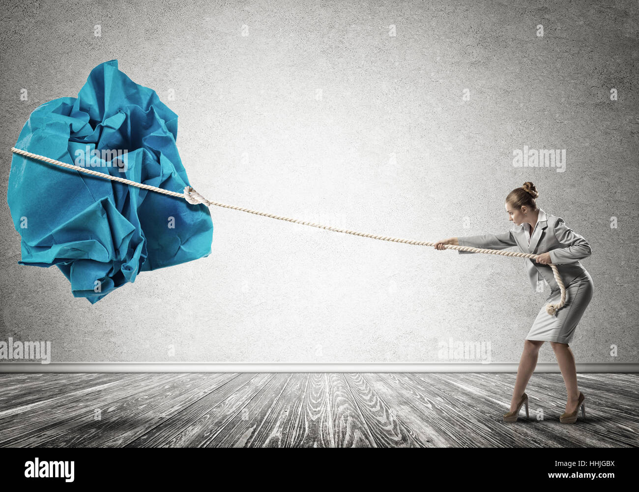 Woman pulling with effort big crumpled ball of paper as creativity sign ...