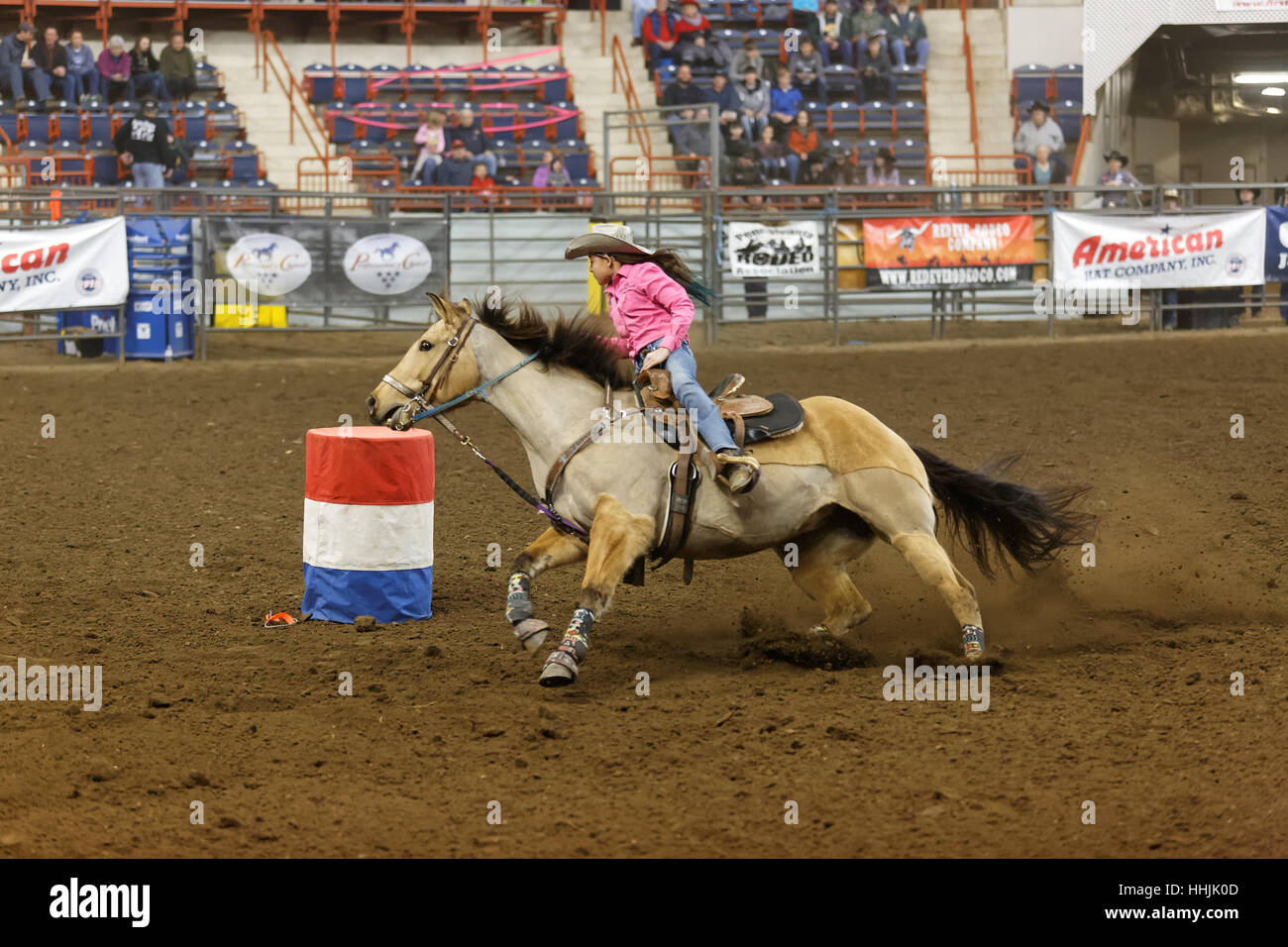 A young cowgirl competes in the high school barrel racing event at the ...