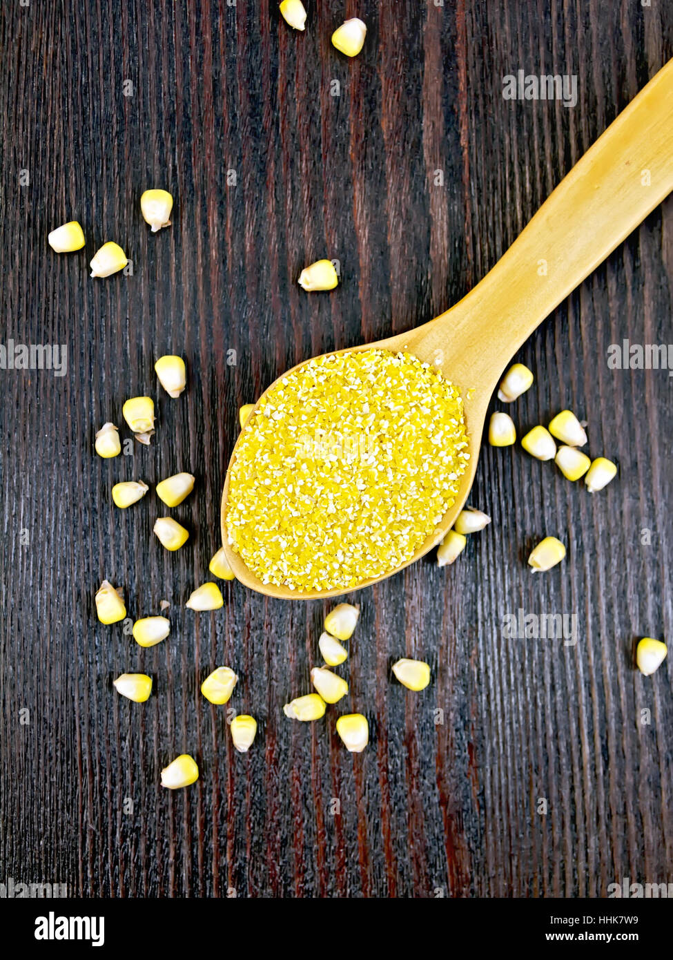 Corn grits in a spoon, corn grains on the background of the wooden ...
