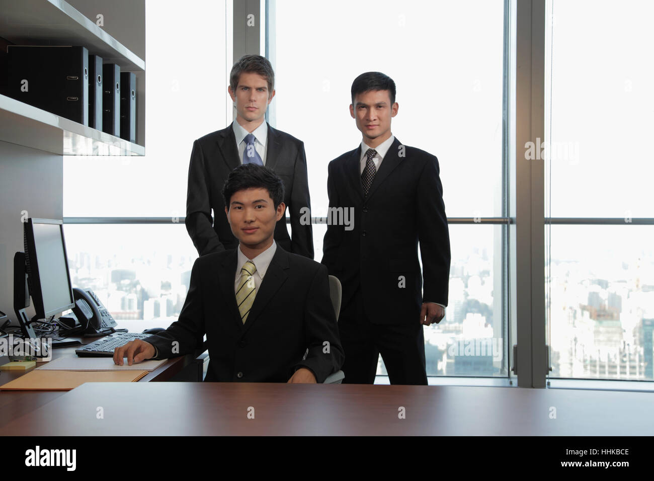 Three businessmen standing together in an office Stock Photo - Alamy