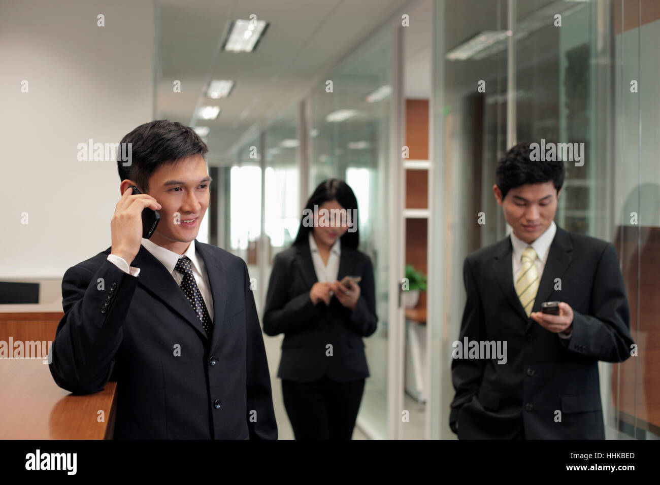 Three businesspeople using their phones in the office Stock Photo - Alamy