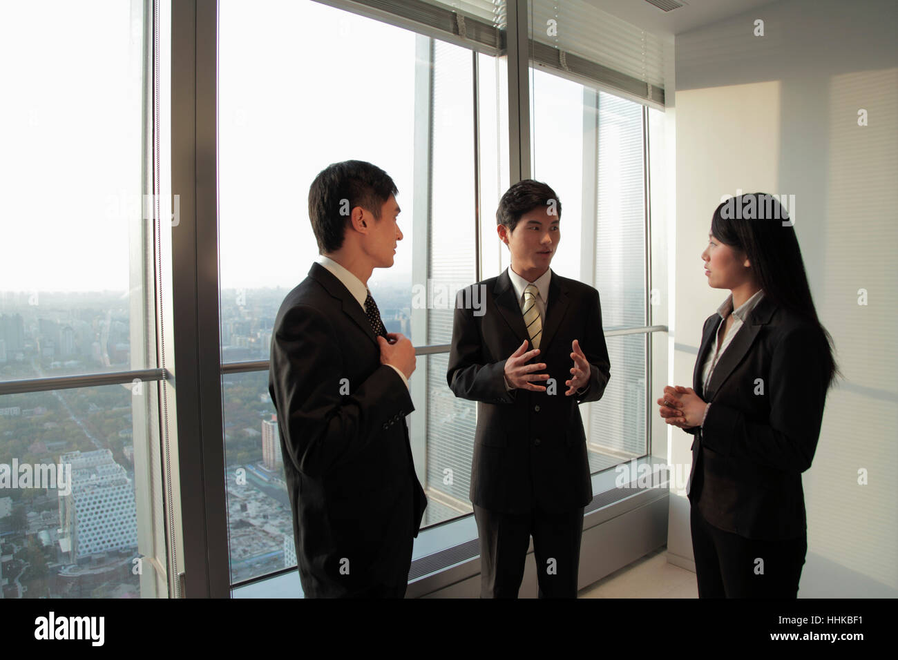 Three businesspeople talking in front of a window Stock Photo - Alamy