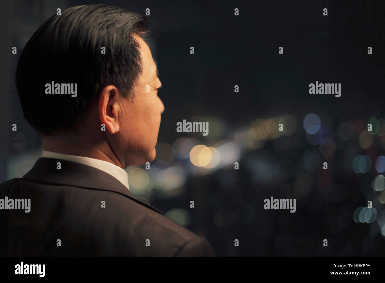 Rear view of man looking out the window at night Stock Photo - Alamy
