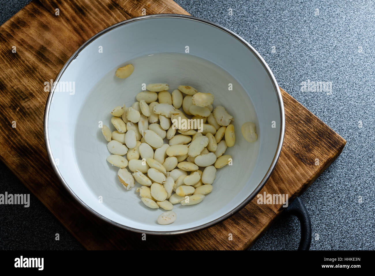 Large white beans soaking in water on a dark wooden cutting board Stock ...