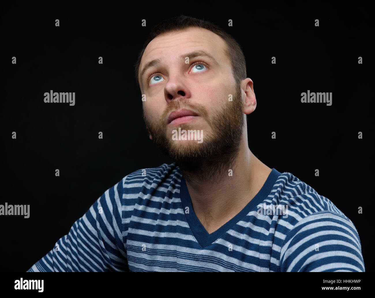 portrait of casual man looking up over black background Stock Photo - Alamy
