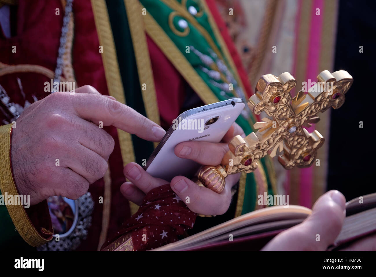 A Syriac Orthodox cleric using a smart phone as he leads a religious ...